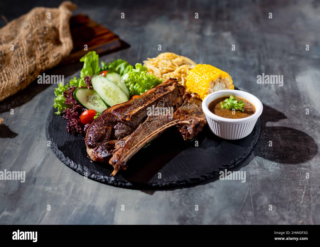 Rosemary Lamp Chop with chili sauce, salad, noodles, corn in a dish top ...