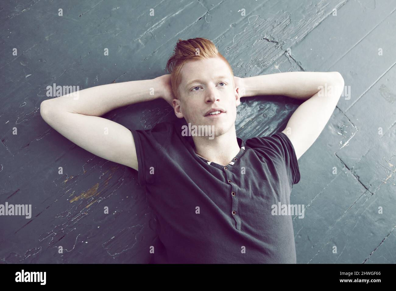 Lost in a day dream. A red haired male lying on the floor and looking ...