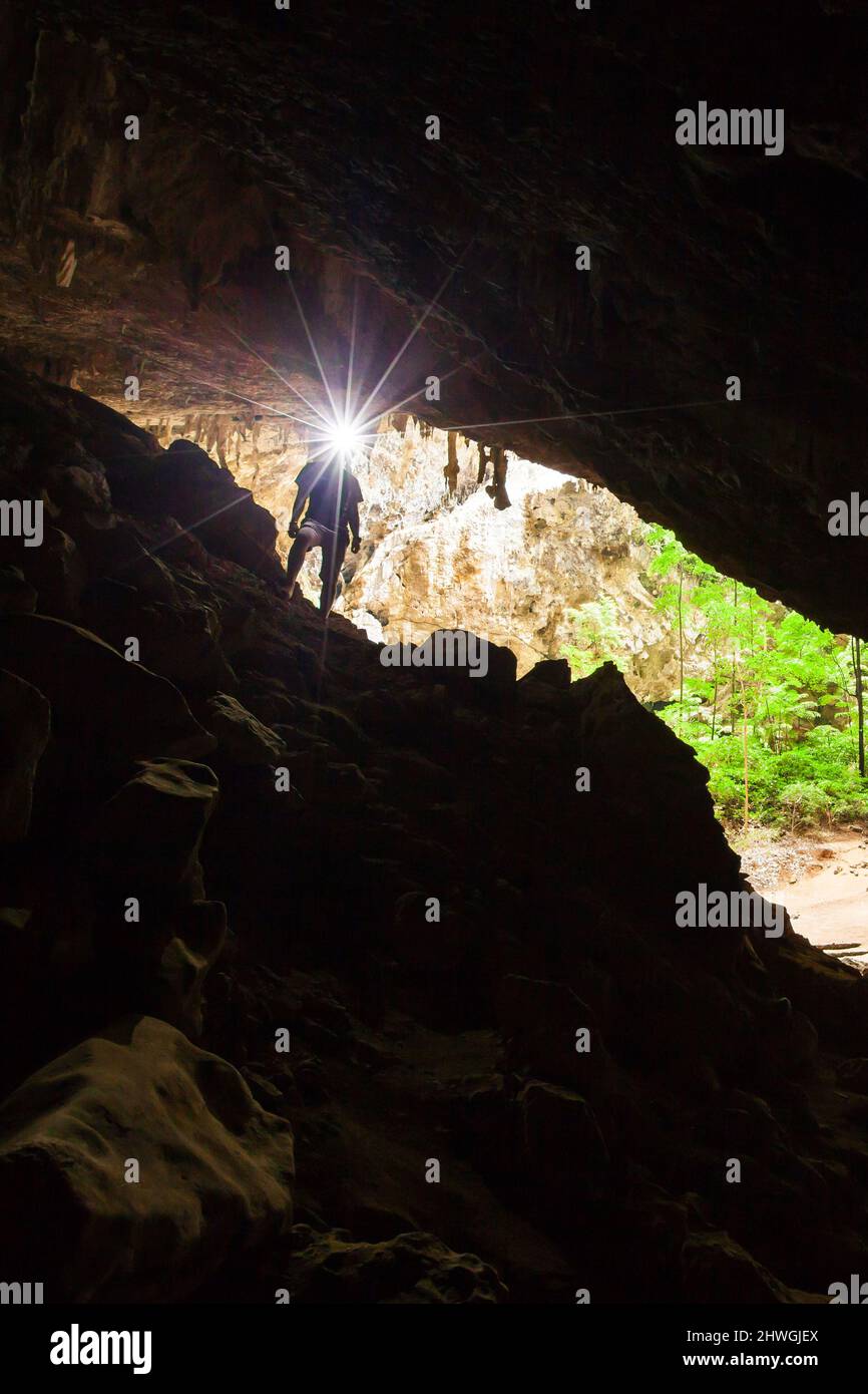 Young man explorer is exploring mystery cave with a torch, Phraya ...
