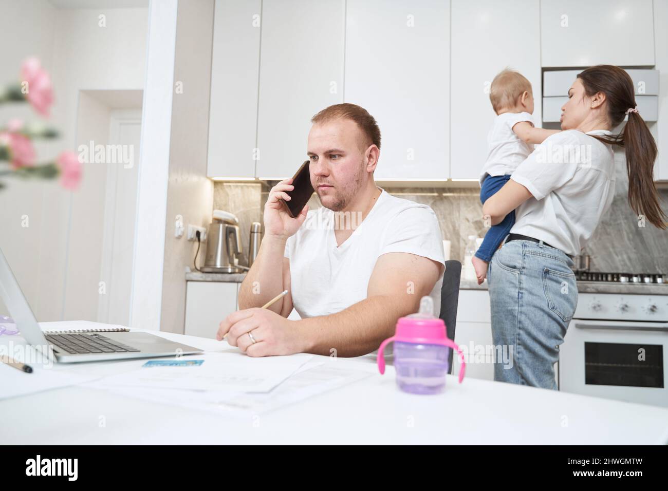 Serious father answering phone while mother calming down child Stock ...