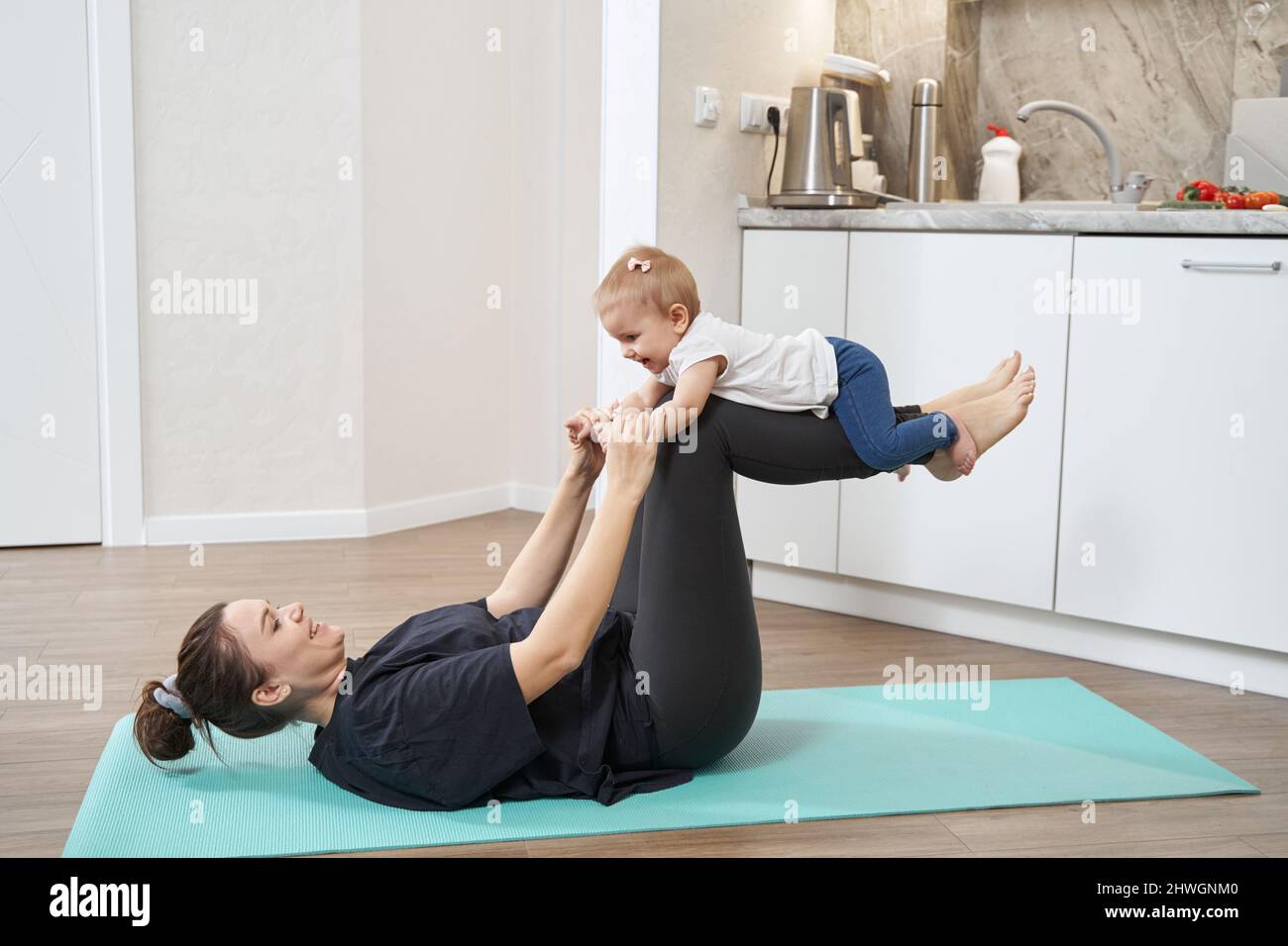 Mother working out on sport mat with her child Stock Photo - Alamy
