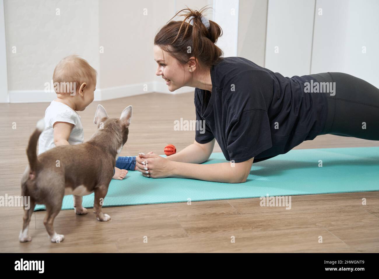Female doing plank with dog and baby before her Stock Photo - Alamy