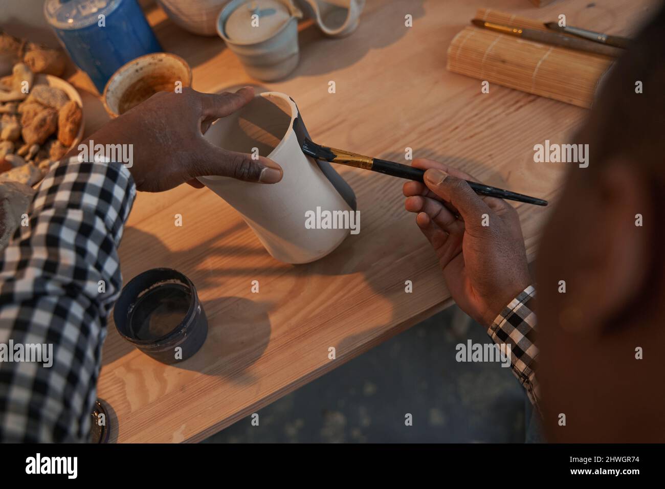Ceramic artist painting exterior surface of pottery piece Stock Photo ...