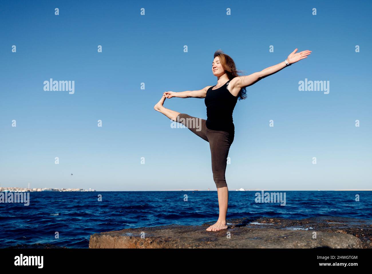 Woman doing yoga background blue sky and sea. Tree pose or vrksasana ...
