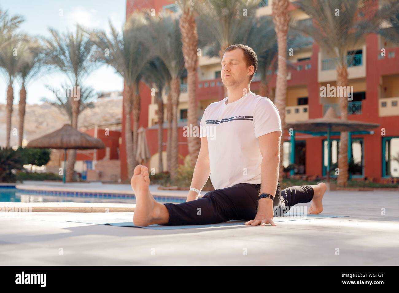 Outdoors Meditation Yoga Man Asana Leg Split Pose Background Pool Palm Trees And Sunlight Stock