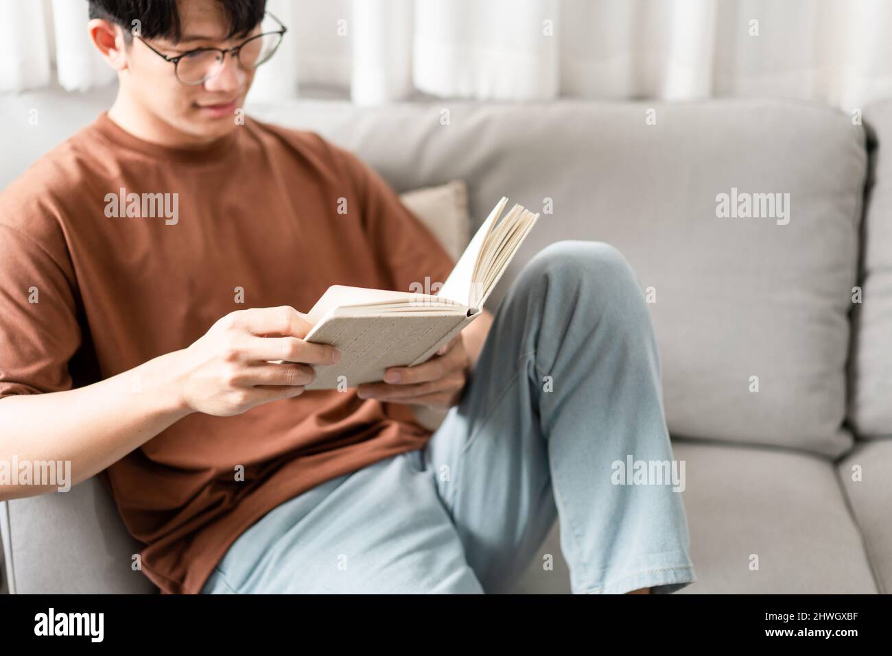 Technology Concept The male with his glasses sitting on the grey sofa ...