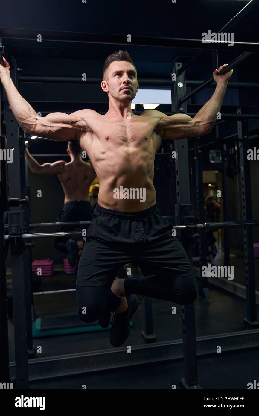 Athletic male person hanging on horizontal bar Stock Photo - Alamy