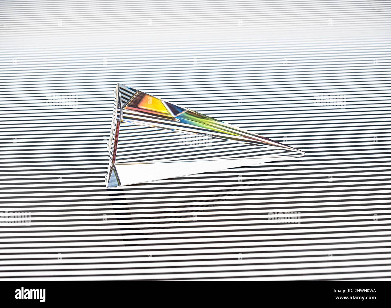 Glass pyramid prism with colorful light reflection on white horizontal ...