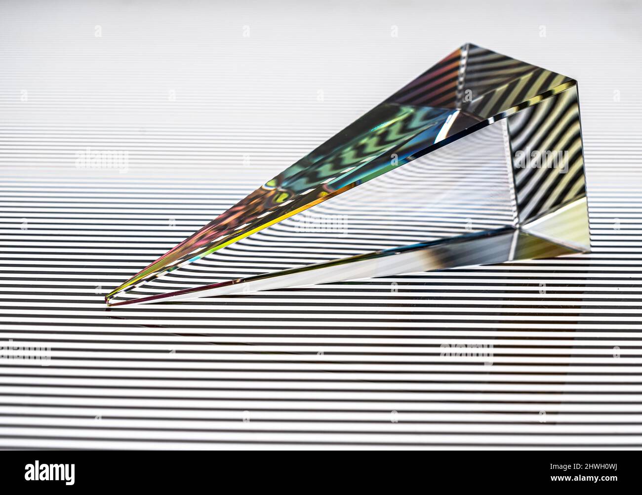 Glass pyramid prism with colorful light reflection on white horizontal ...