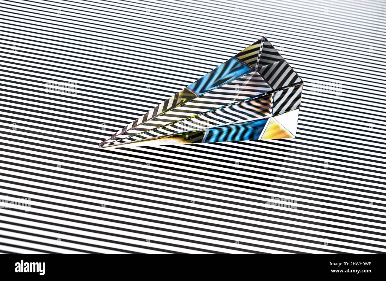 Glass pyramid prism with colorful light reflection on white horizontal ...