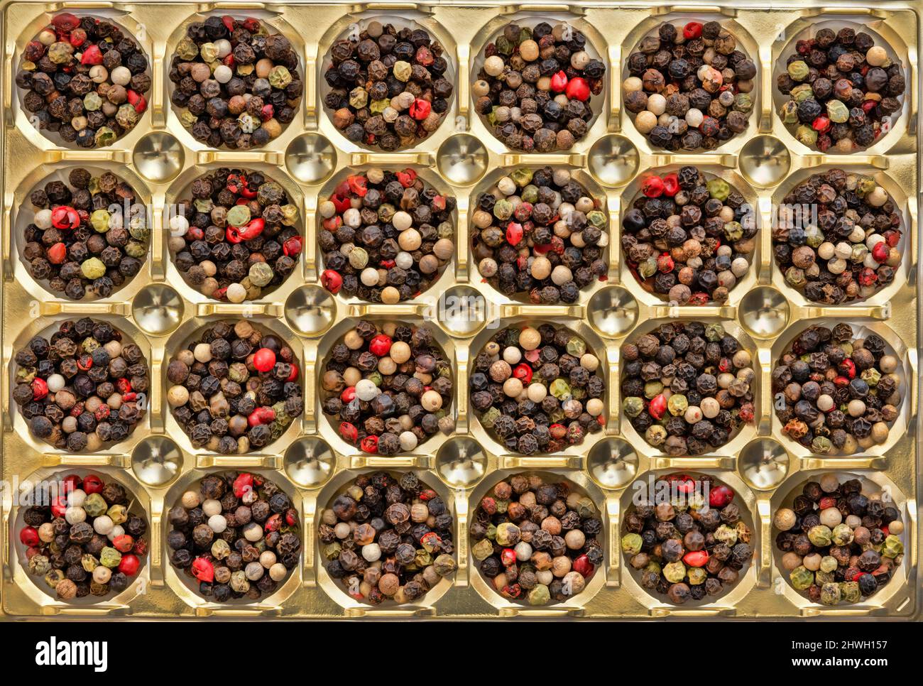 Mixed peppercorns fill golden plastic shapes. Different colored ...