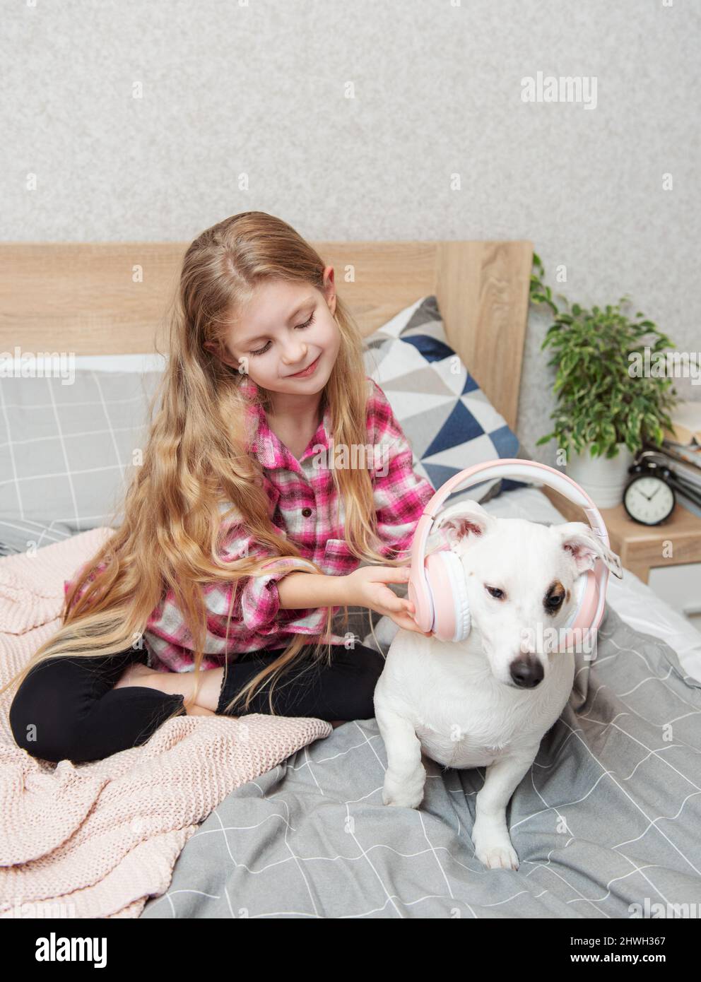 Child girl and dog. Little girl puts headphones on her dog Stock Photo ...