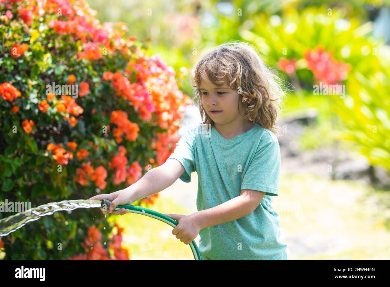 Child playing with garden hose in backyard. Funny excited kid having ...