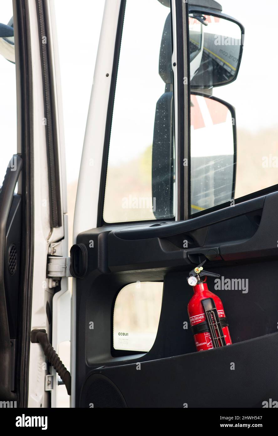 Red fire extinguisher in a black truck door Stock Photo - Alamy