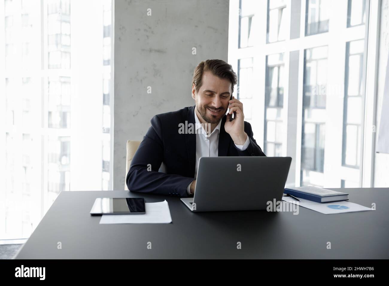 Happy concentrated young businessman multitasking in modern office ...
