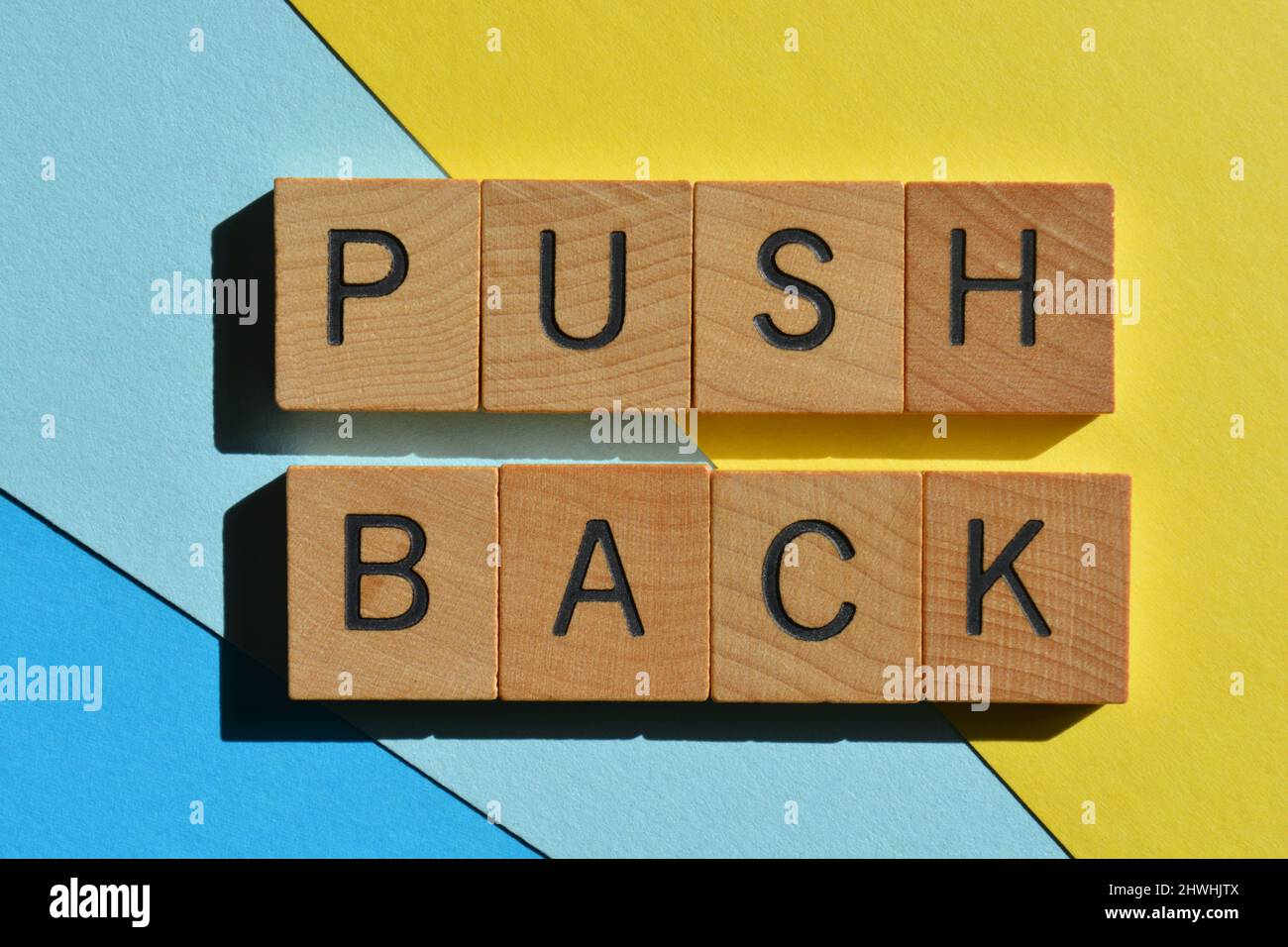 Push Back, words in wooden alphabet letters isolated on blue and yellow ...