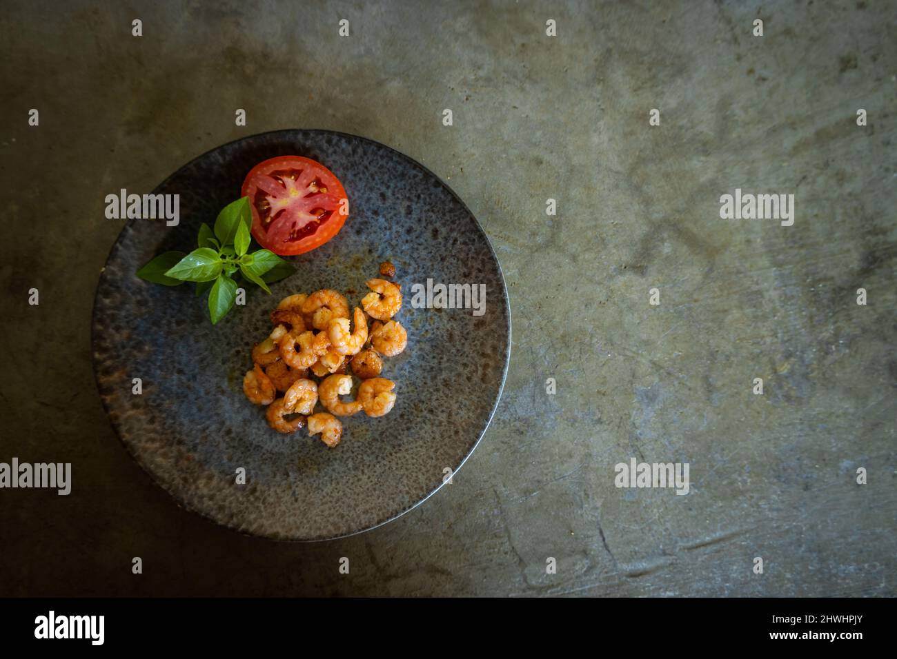 Delicious freshly cooked shrimp on a gray plate next to a tomato and ...