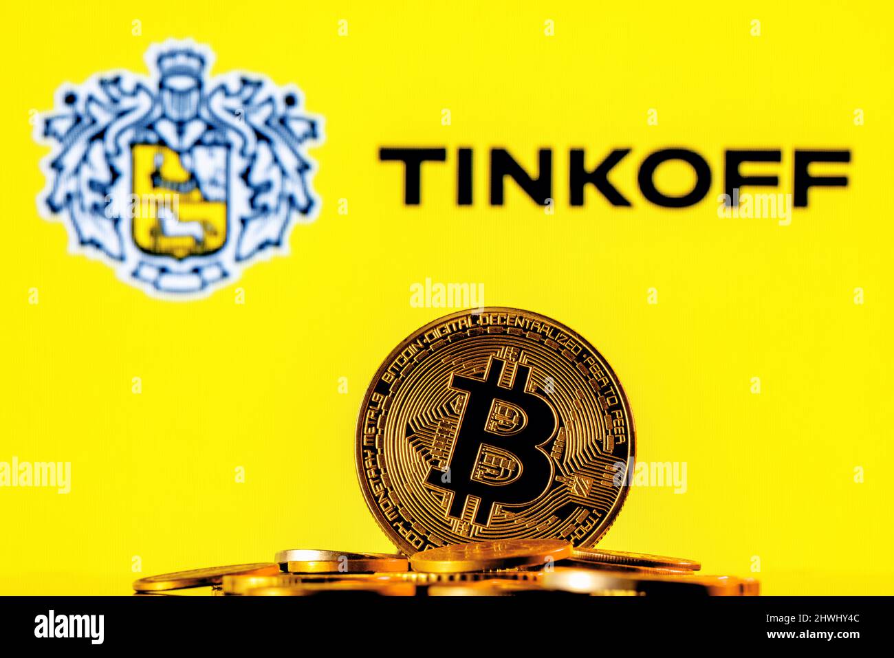 Golden bitcoin in pile of coins on background of Tinkoff bank logo ...