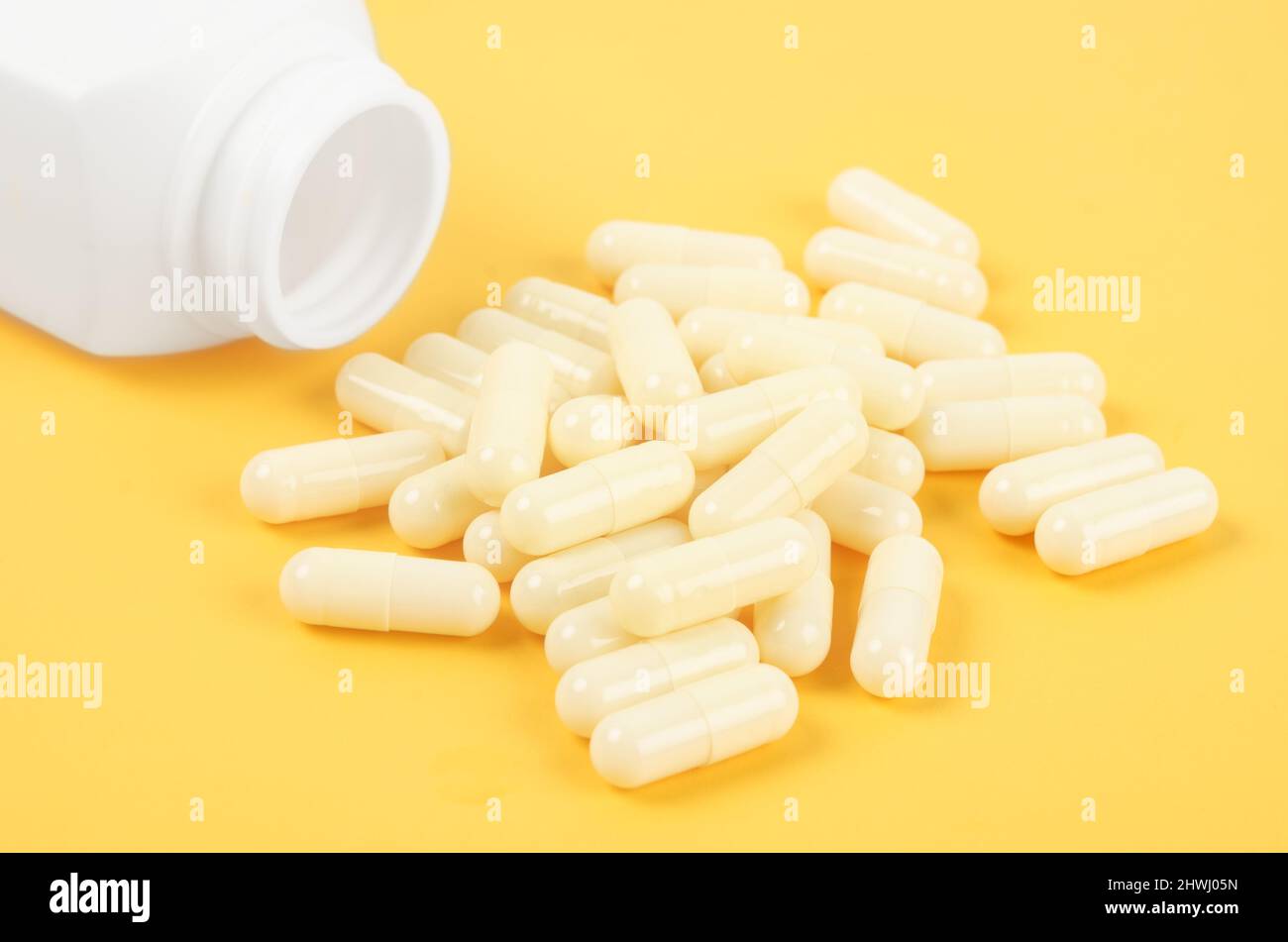 Yellow pharmaceutical medicine capsules over yellow background. White ...