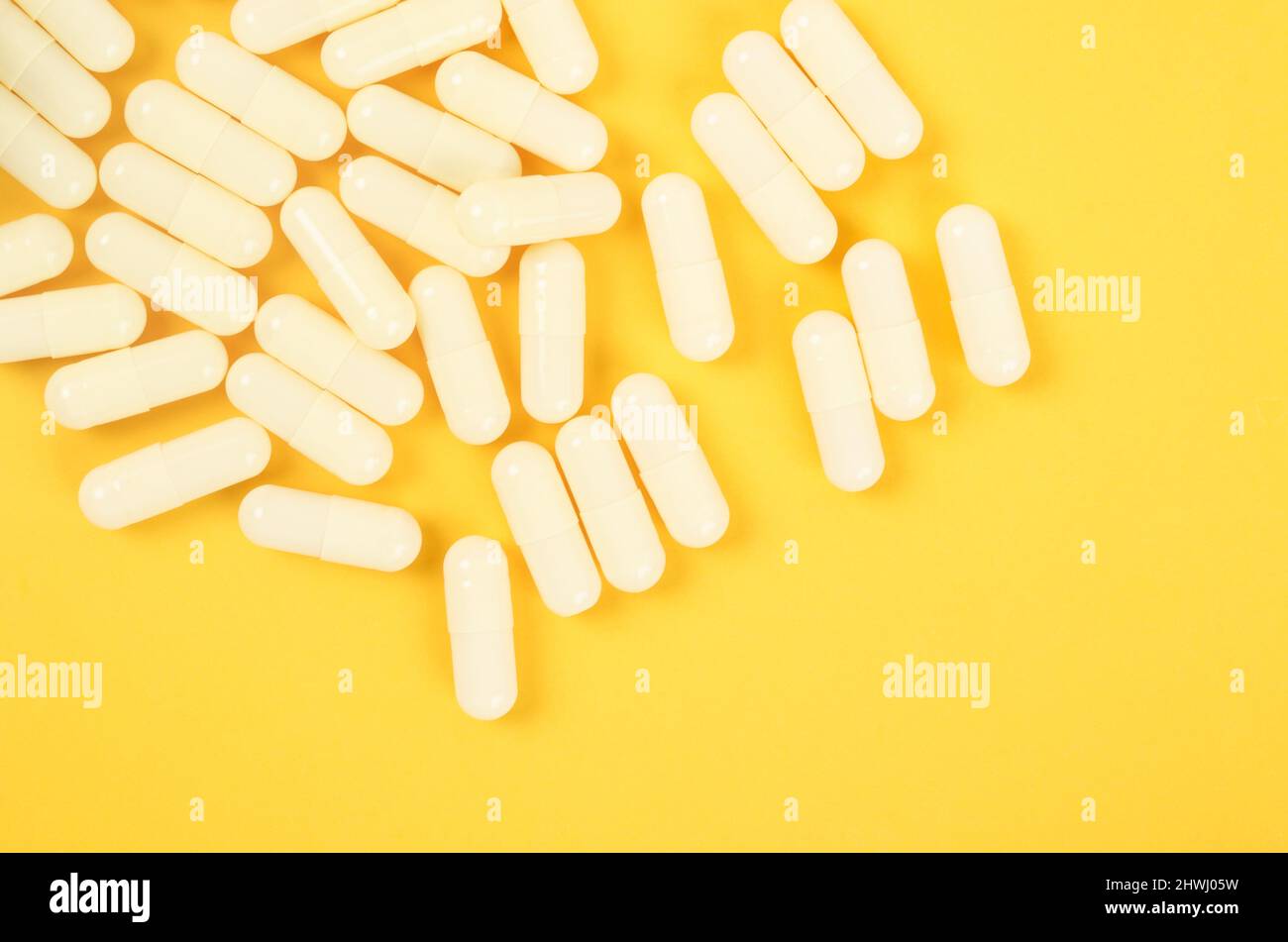 Yellow pharmaceutical medicine capsules over yellow background Stock ...
