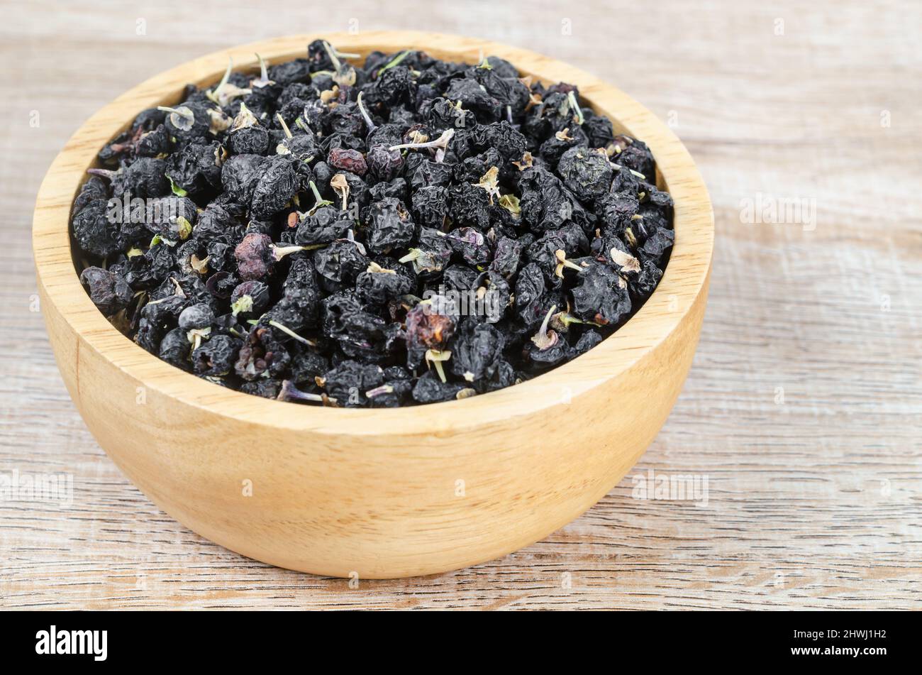 Black wolfberries or black goji berries, in a wooden bowl on table Stock Photo - Alamy