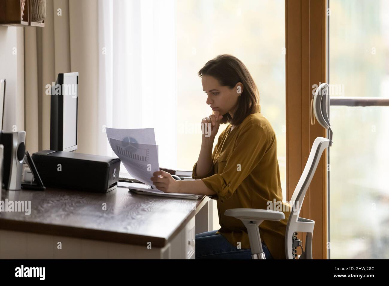 Serious woman sit at desk holds sheets reviewing infographic Stock ...