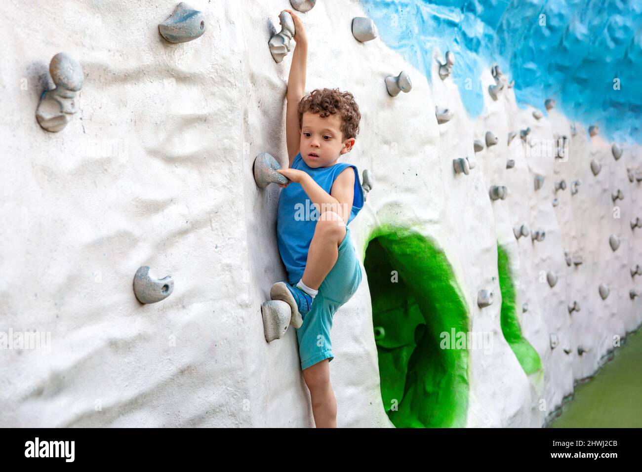 small Caucasian boy climbing up a climbing wall Stock Photo - Alamy