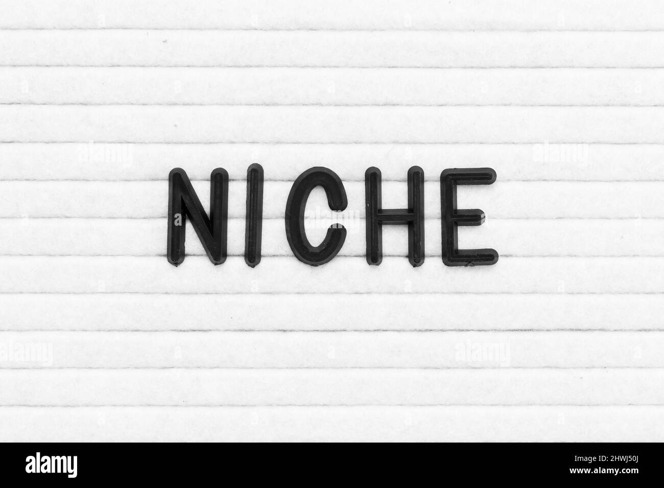 Black color letter in word niche on white felt board background Stock ...