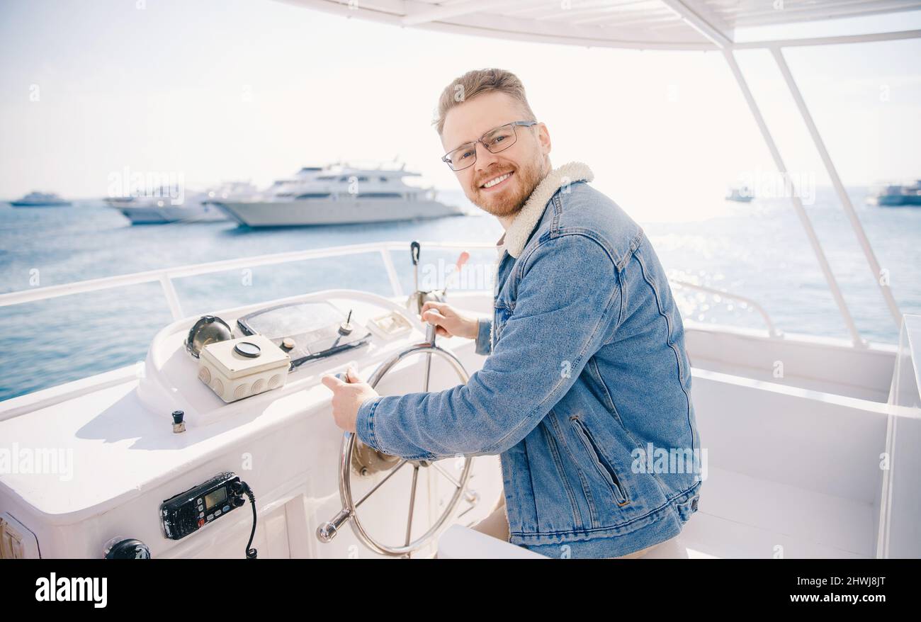 Portrait smile happy man driver captain of white luxury yacht holding ...