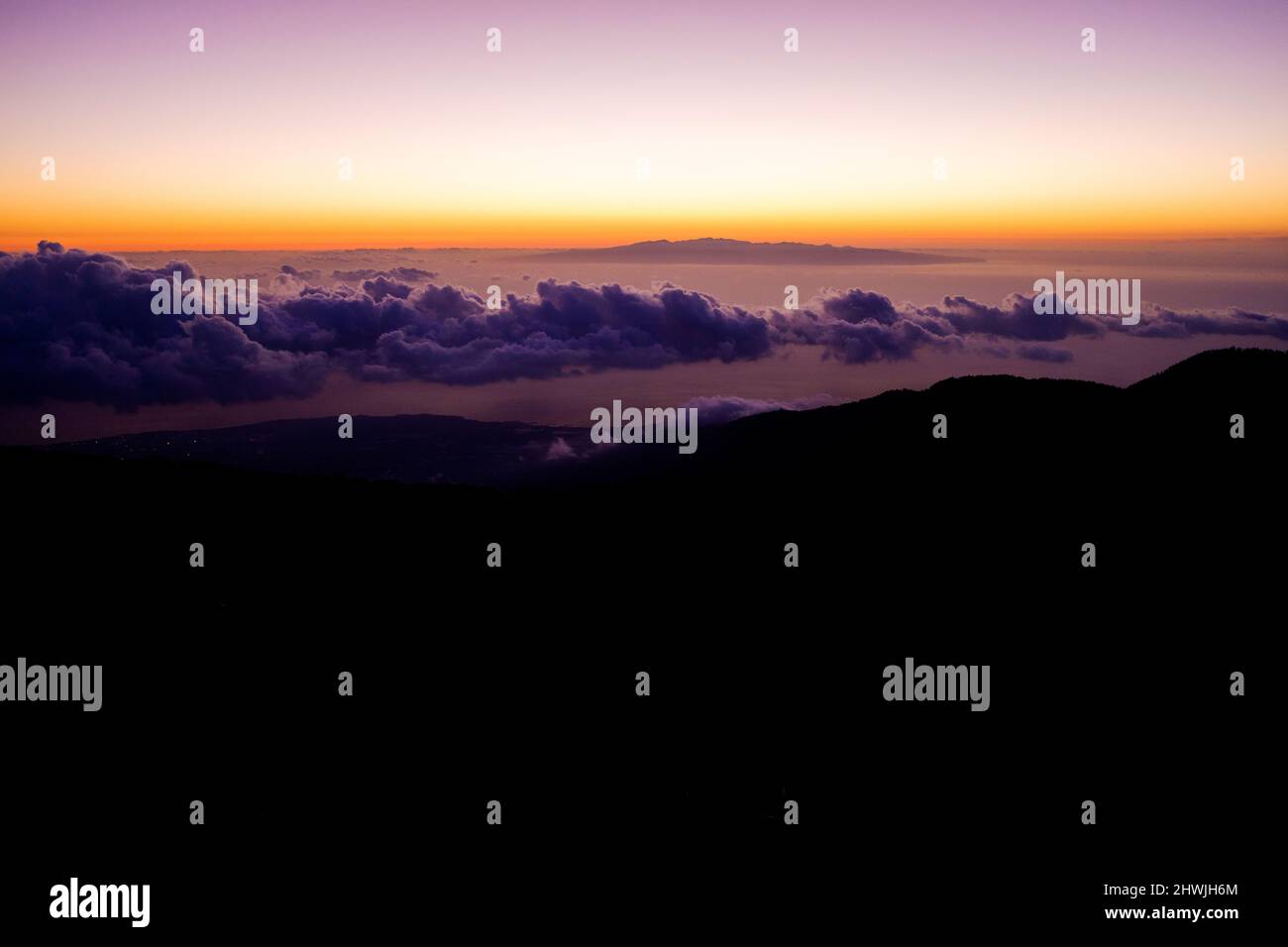 Sunset over the top of a mountain, over the clouds below, a mysterious atmosphere copy space ...