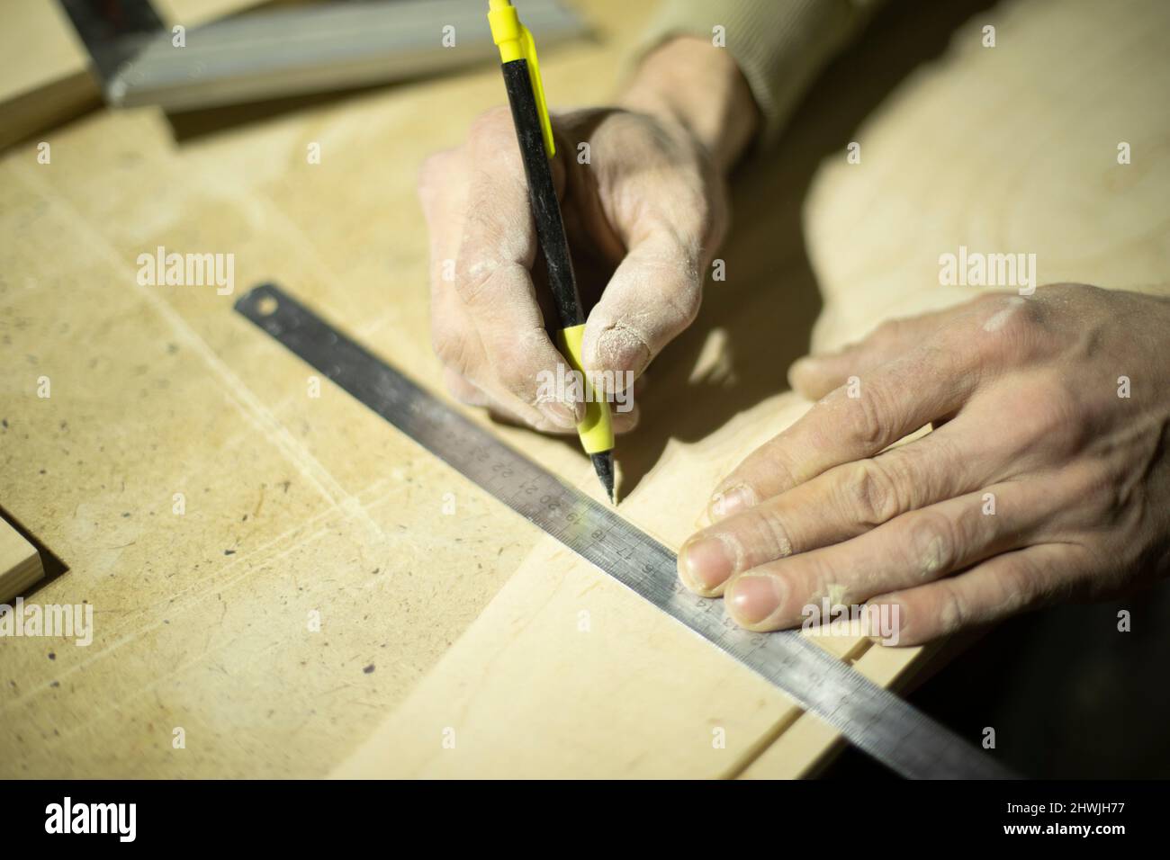 Marking on ruler with pencil. Drawing line on tree. Hands of carpenter ...