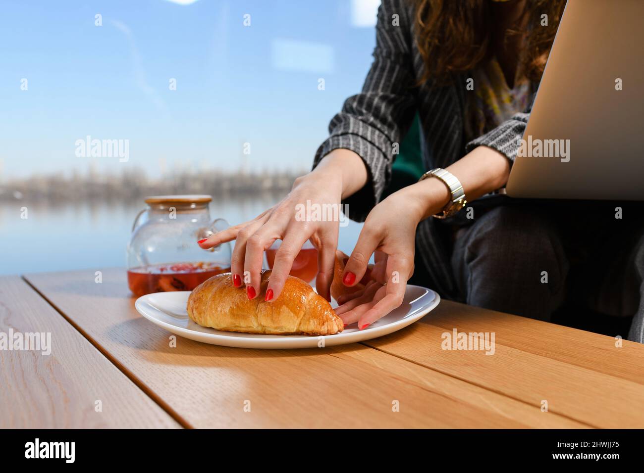 Woman hand hold breakfast croissant in plate on table, morning tea and ...