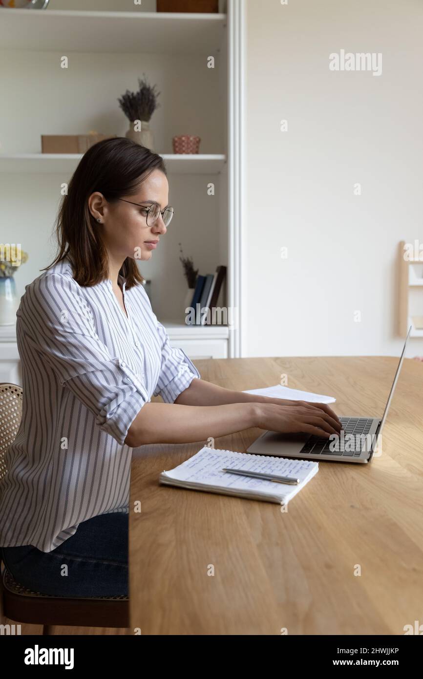 Young serious woman sit at table typing on laptop keyboard Stock Photo ...