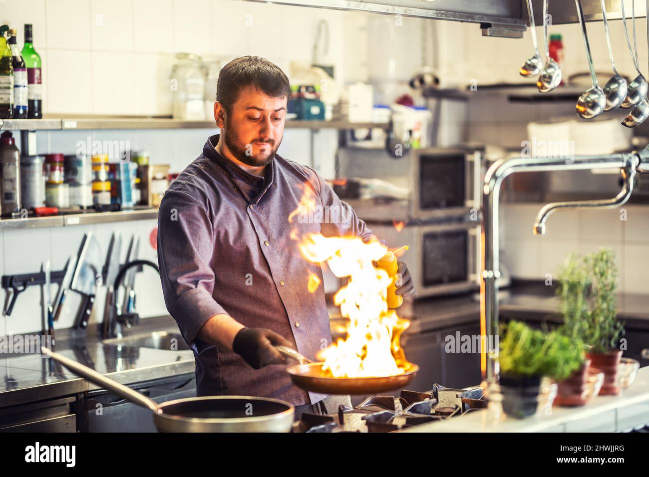 Chef flamboyants in the restaurant kitchen with flames coming out of ...