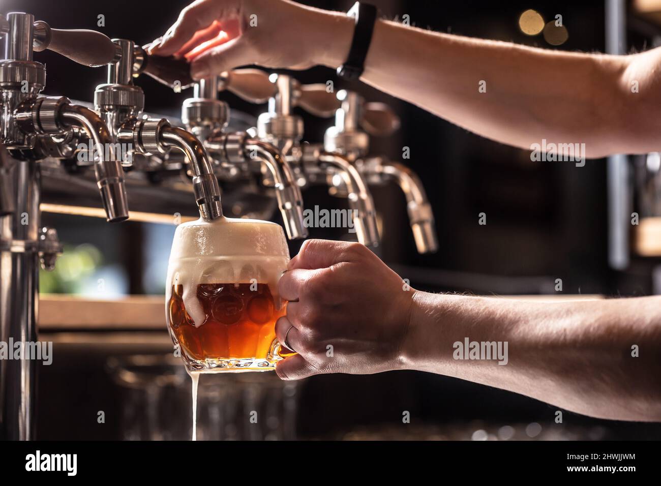 Hands of the pub employee tapping beer into a rounded mug Stock Photo ...