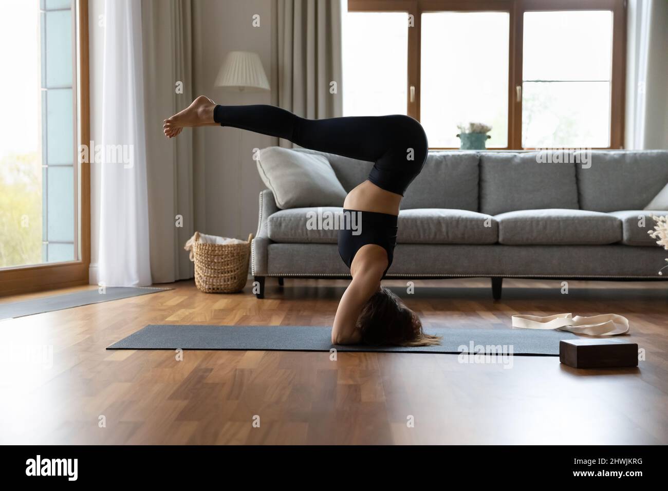 Woman doing supported headstand in modern living room Stock Photo - Alamy