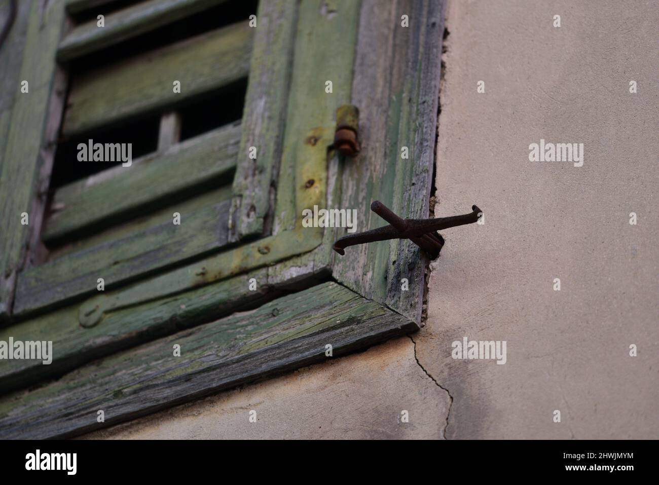Antique window with aged green wooden shutters and a rusty shutter dog ...