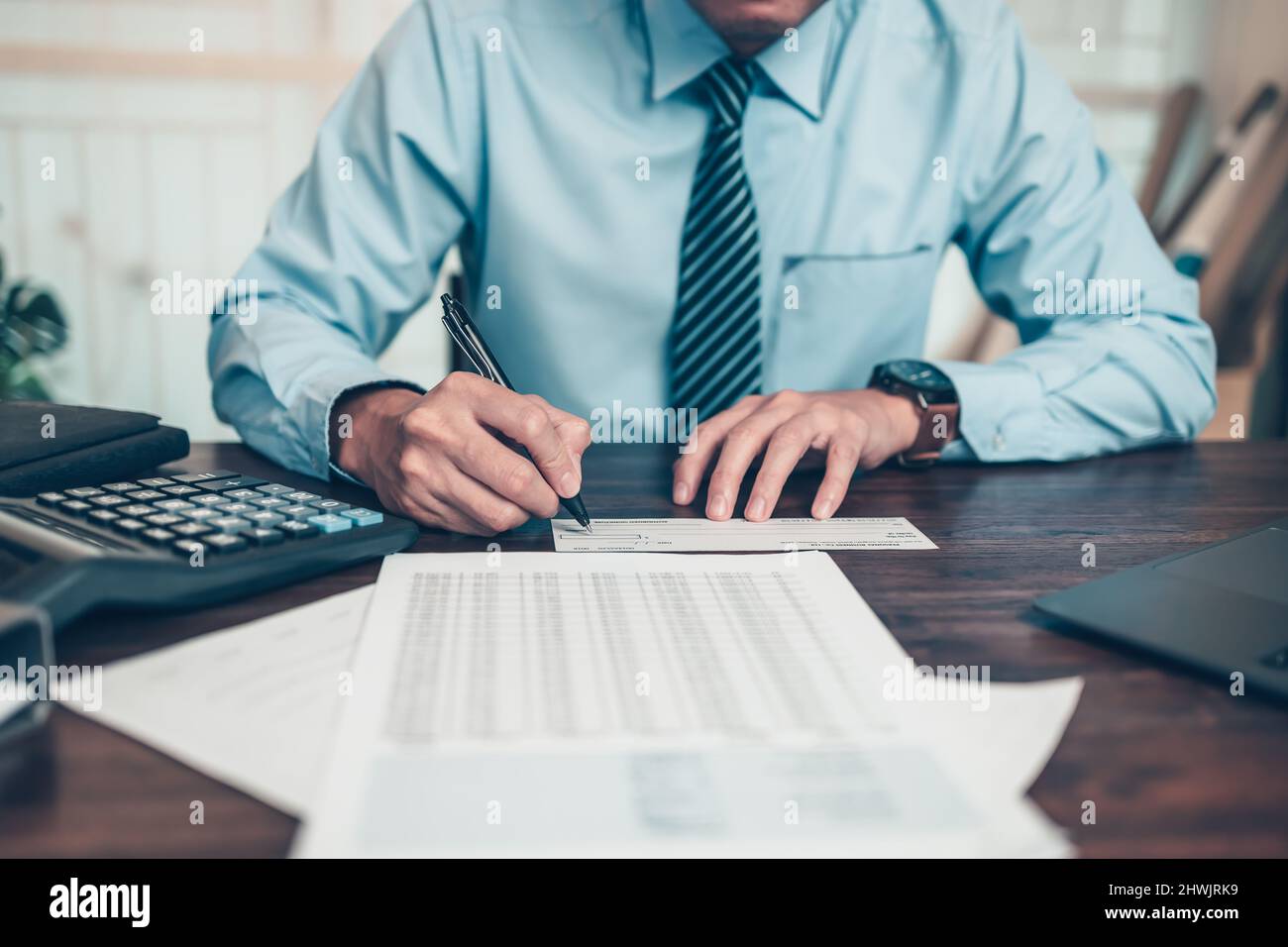 Business man hand writing and signing white blank bank check book and ...