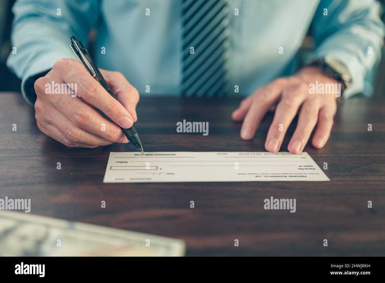 Business man hand writing and signing white blank bank check book and ...