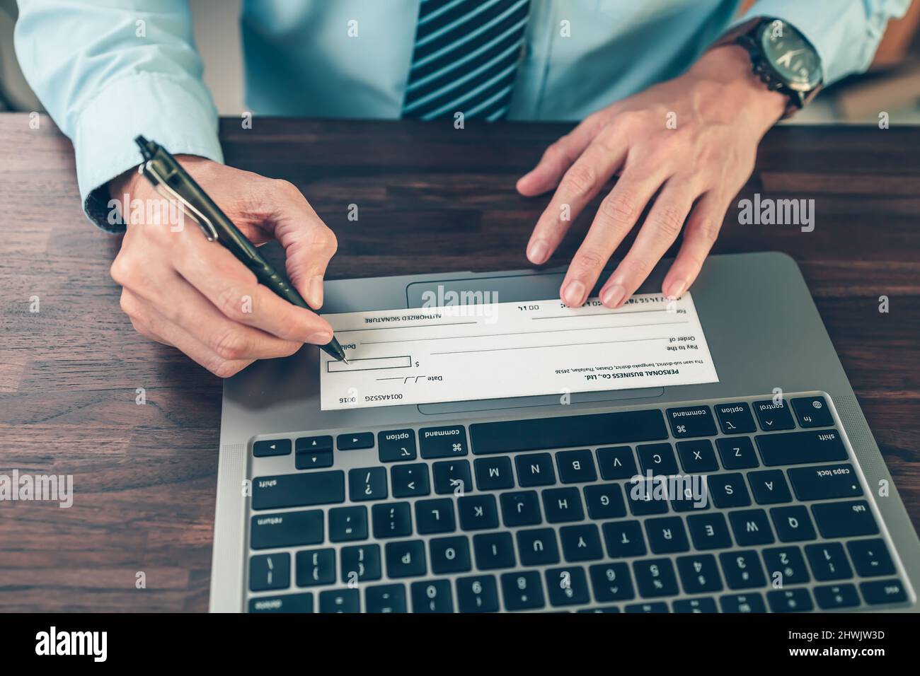 Business man hand writing and signing white blank bank check book and ...