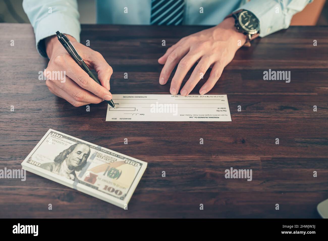 Business man hand writing and signing white blank bank check book and ...