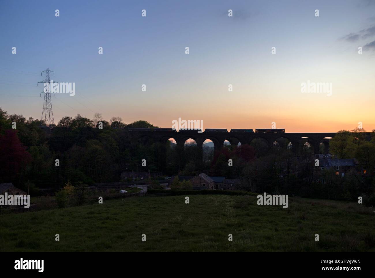 Silhouette of a GB Railfreight class 66 locomotive crossing chapel ...
