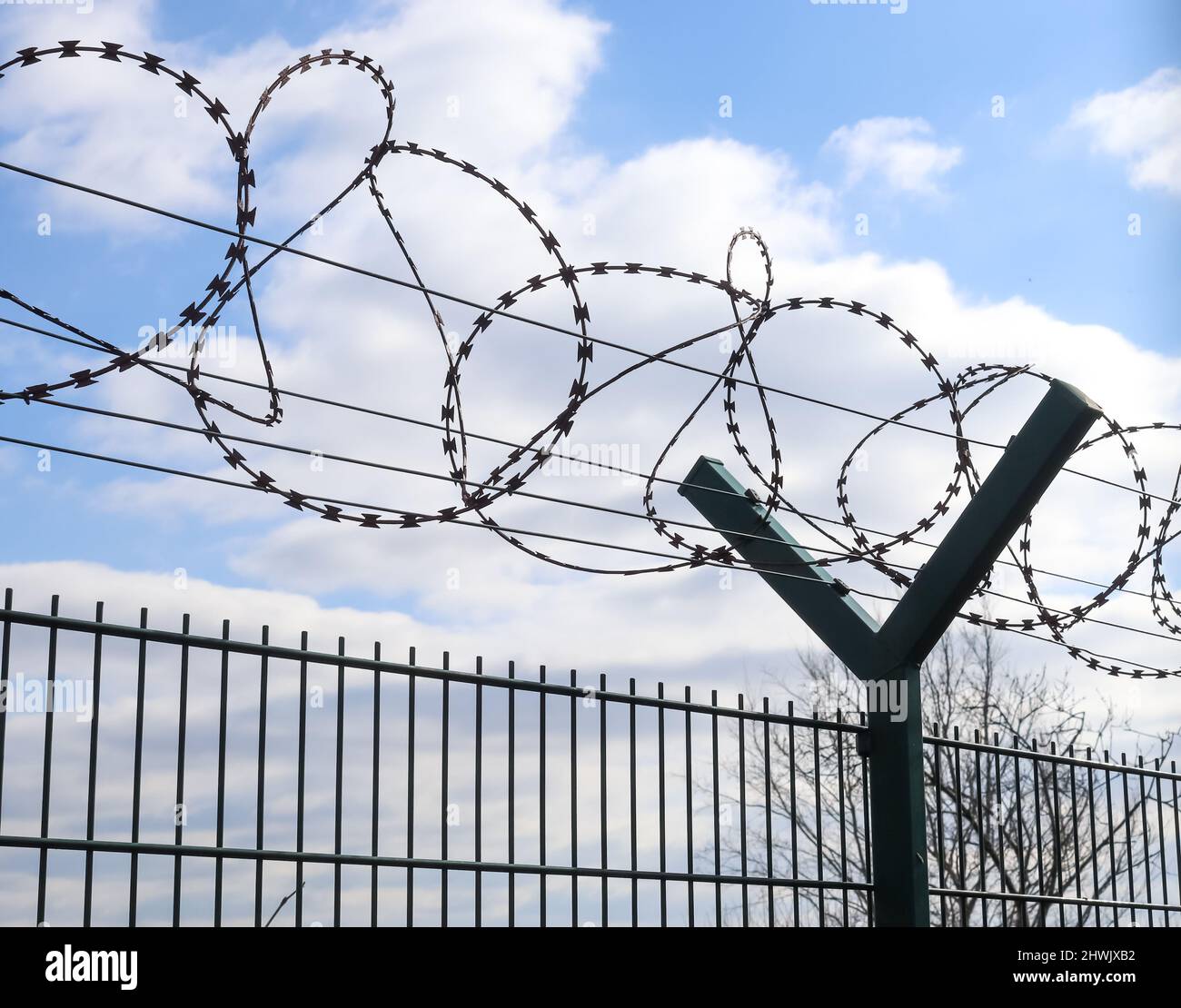 Barbed wire against a cloudy sky on a big fence at a border Stock Photo ...