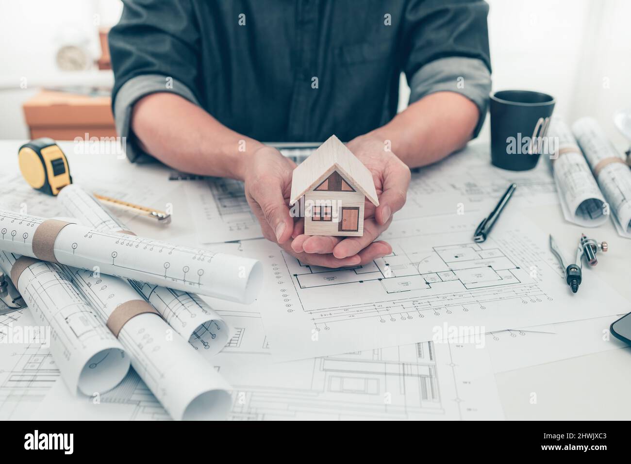Architect engineer hands hold and protect mini house model on bueprint. Protect House, cost ...