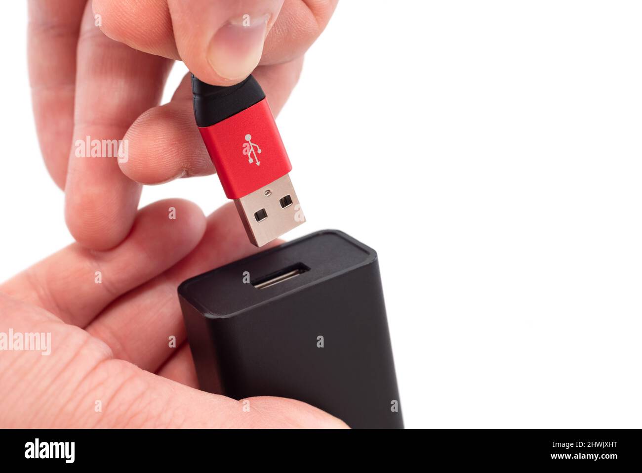 Hands connect the usb cable to the socket on a white background close ...