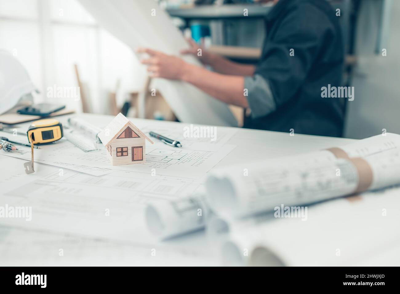 Mini model house on blueprint plan while architector sitting and read ...