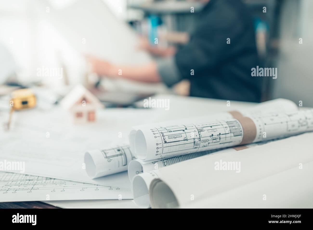 Architect rolls and plans on the table and architect engineer use pen drawing design working on ...
