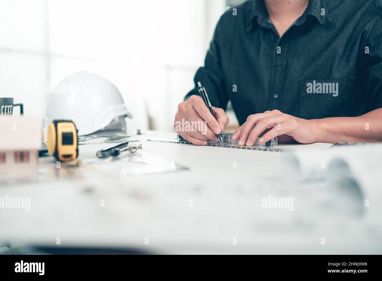 Architect engineer use pen and mini T-slide drawing design working on bueprint. House planning ...