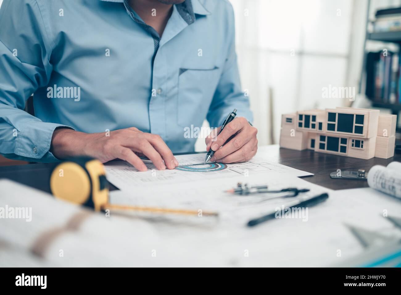 Architect engineer use pen and angle protector drawing design working on bueprint. House ...