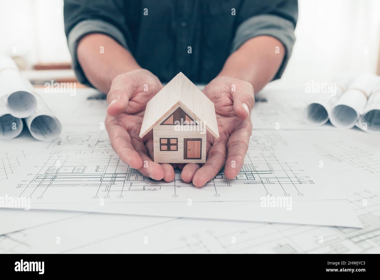 Architect engineer hands hold and protect mini house model on bueprint. Protect House, cost ...
